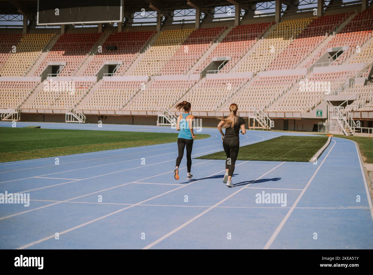 Female friends running around the stadium together Stock Photo - Alamy