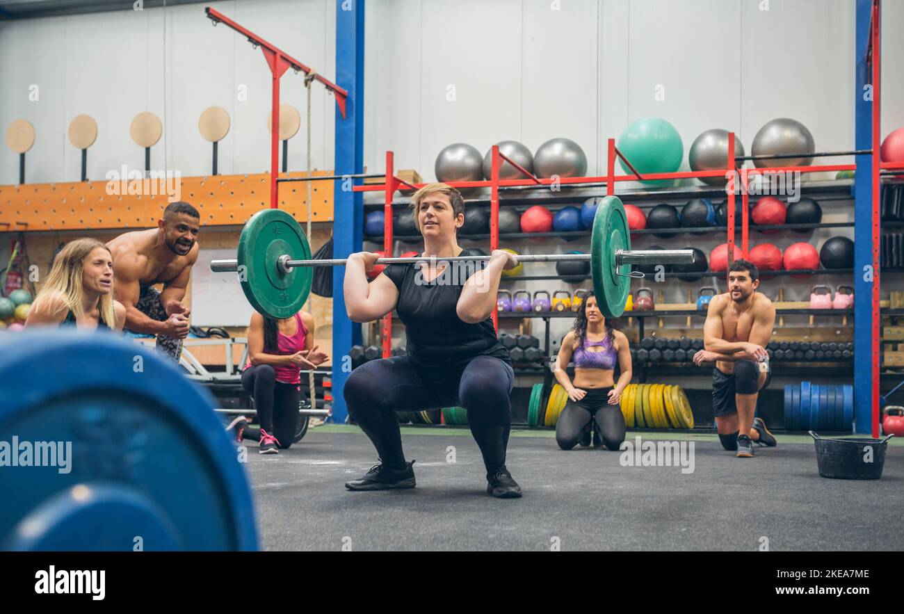 Woman weightlifting while her gym mates cheering her on Stock Photo - Alamy