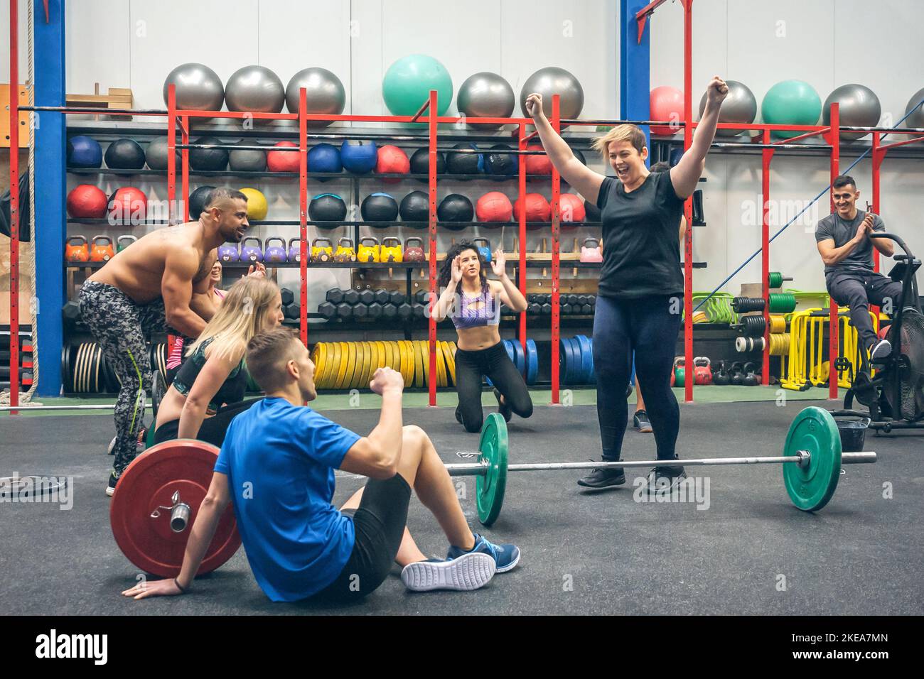 Happy woman celebrating her weightlifting achievement while her gym ...