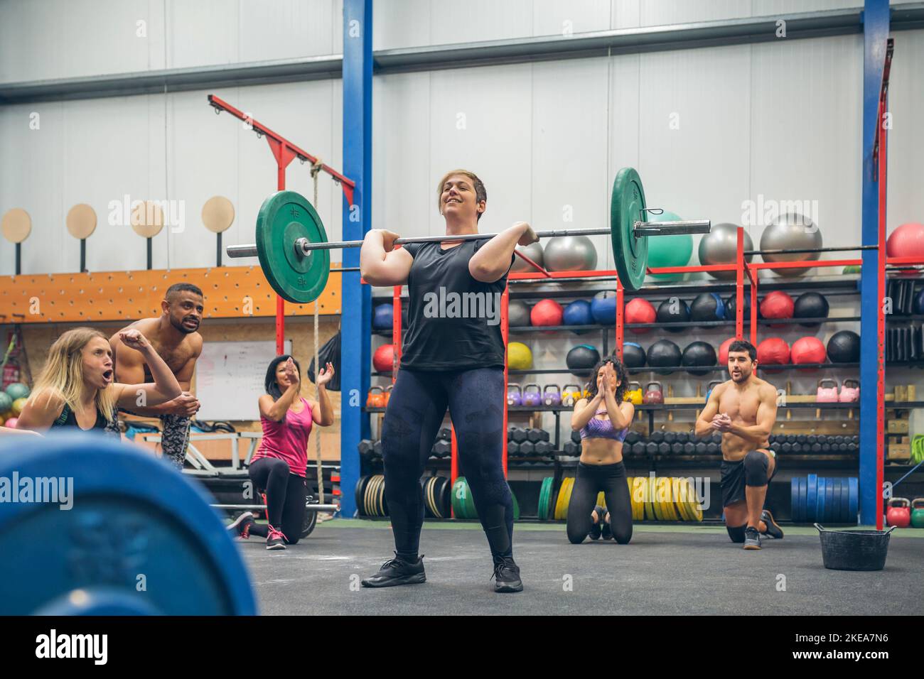 Proud woman weightlifting while her gym mates cheering her on Stock ...