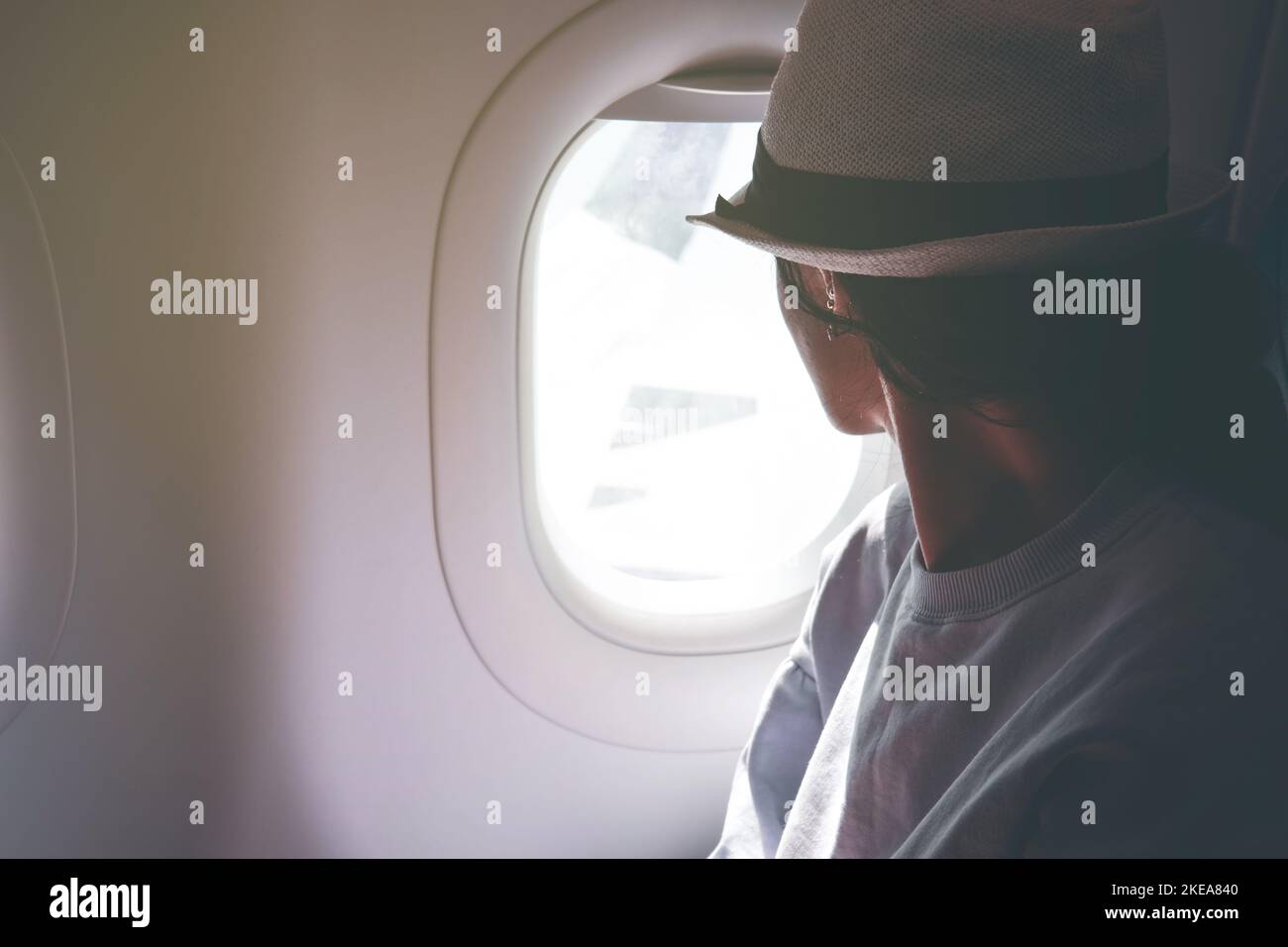 Woman looks out the window of an flying airplane wings view. Young ...