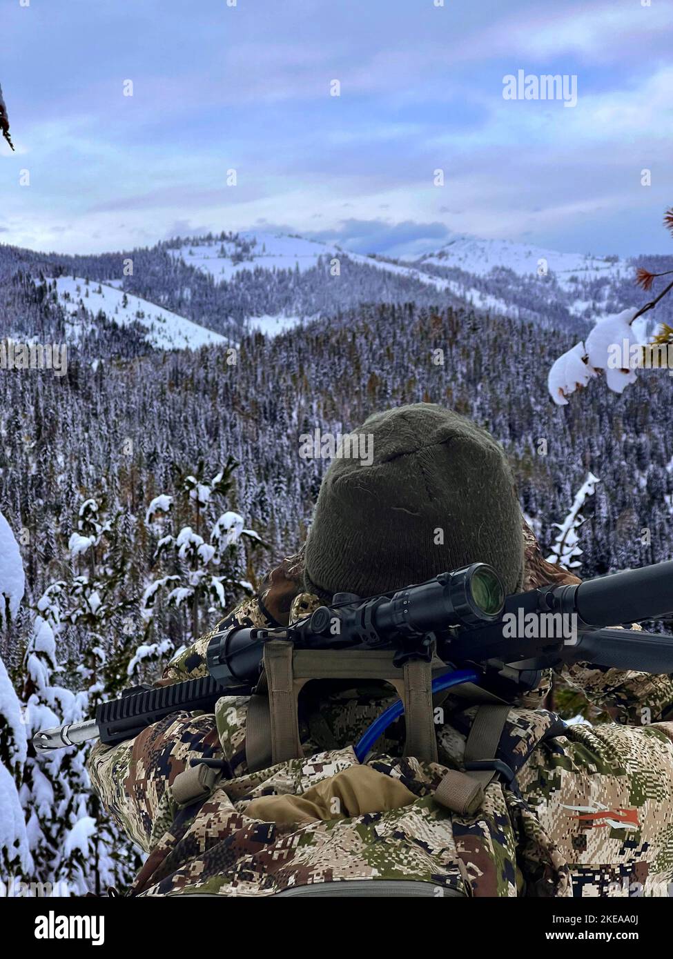 A vertical shot of a man with a sniper rifle on his back overlooking ...