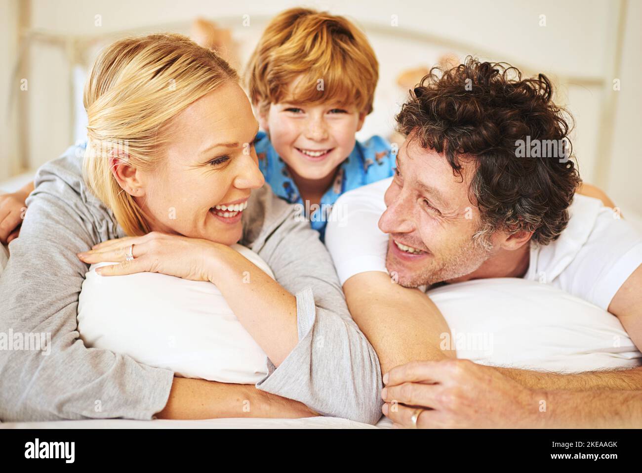 Hes always close to Mom and Dad. Portrait of a young boy lying down on ...