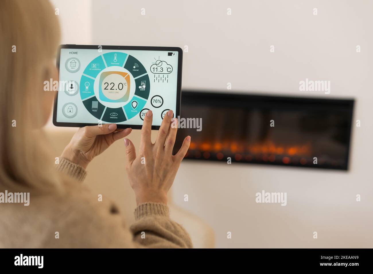 Holding digital tablet in cozy living room with fireplace on background ...