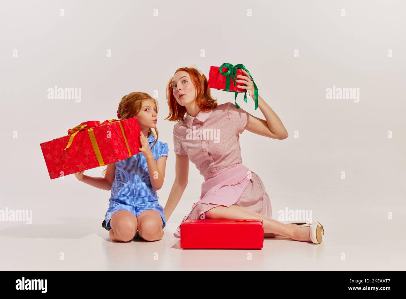 Portrait of beautiful woman and little girl, child shaking present box ...