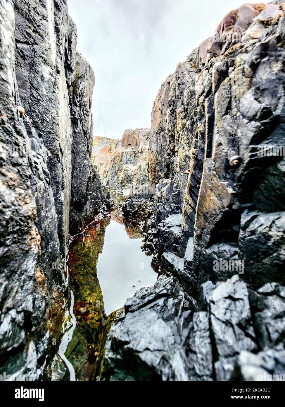 A vertical view through steep rocks of a narrow river flowing through ...