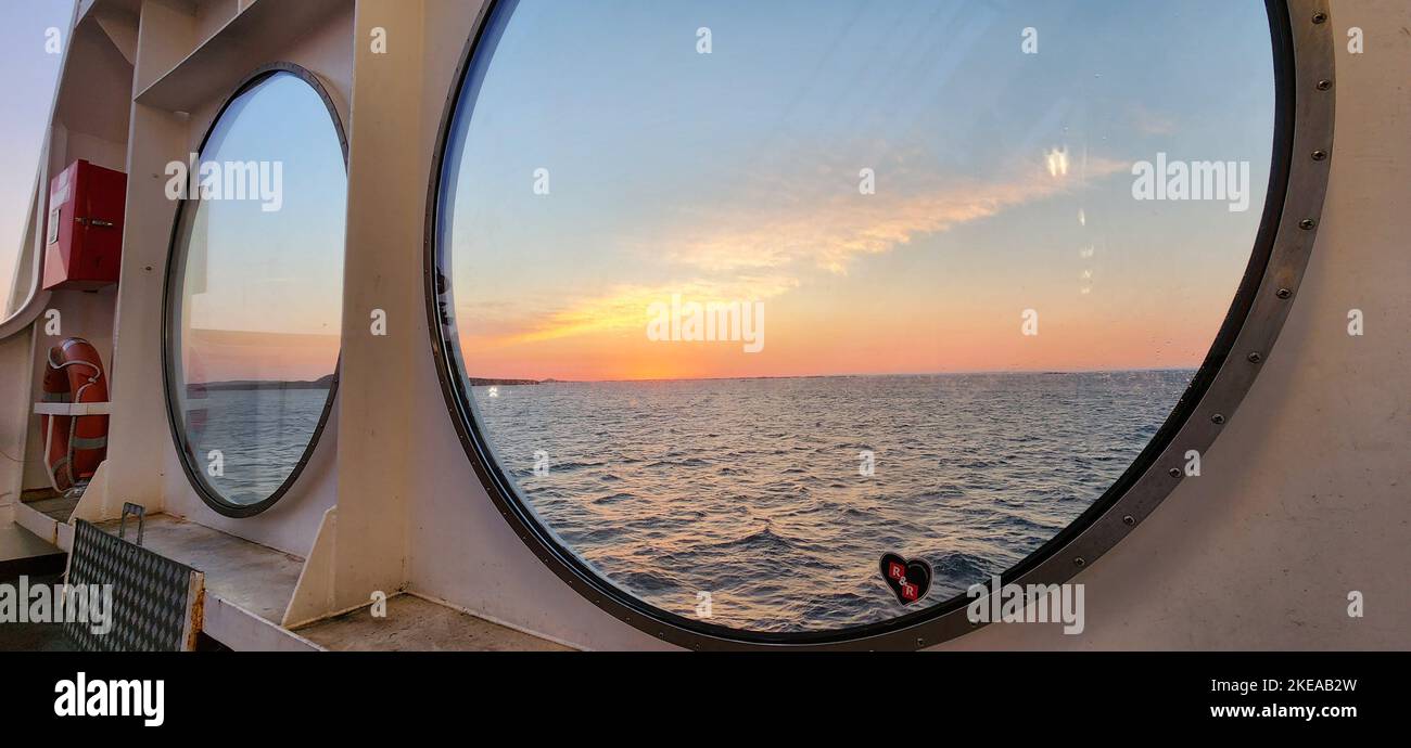 A breathtaking sunset view over the sea behind round boat windows Stock ...