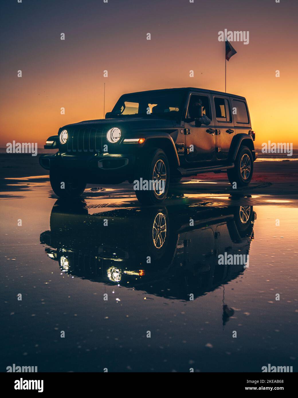 A vertical shot of a Jeep Wrangler reflected on in the puddle against ...