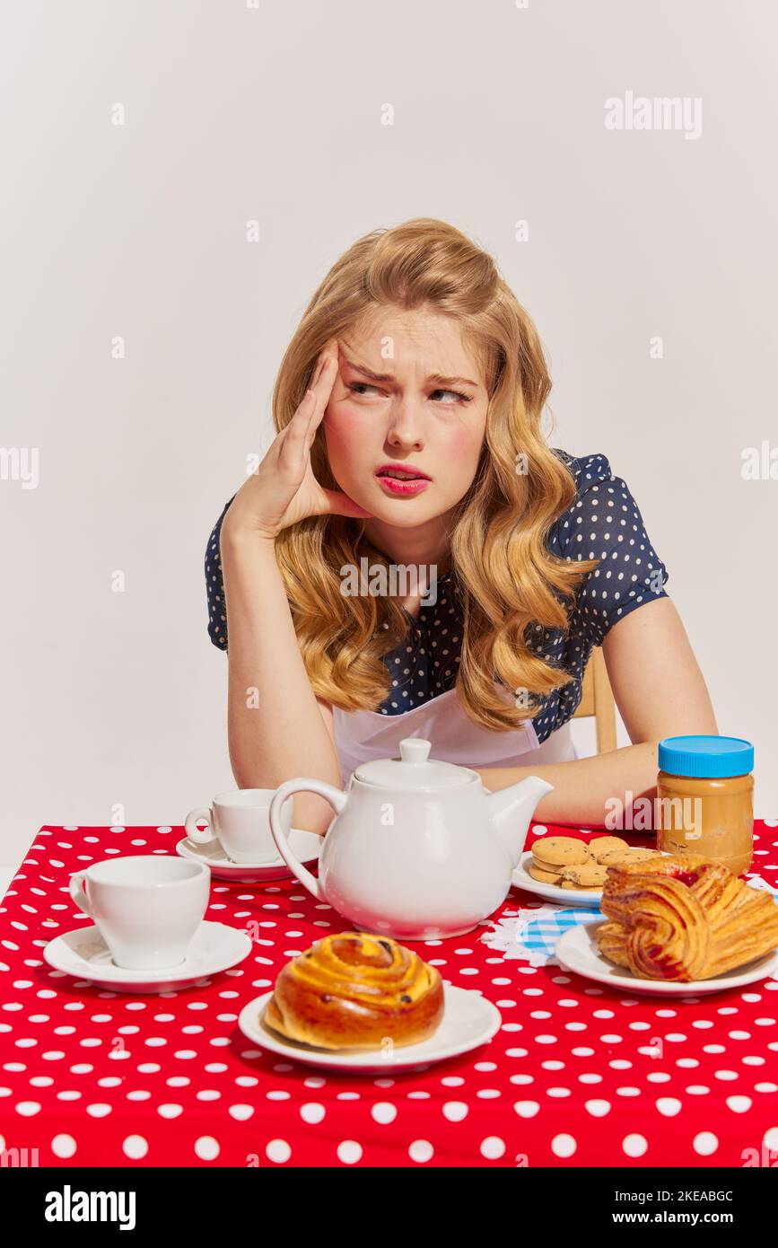 Portrait of young emotive, beautifl girl sitting at the table isoated ...