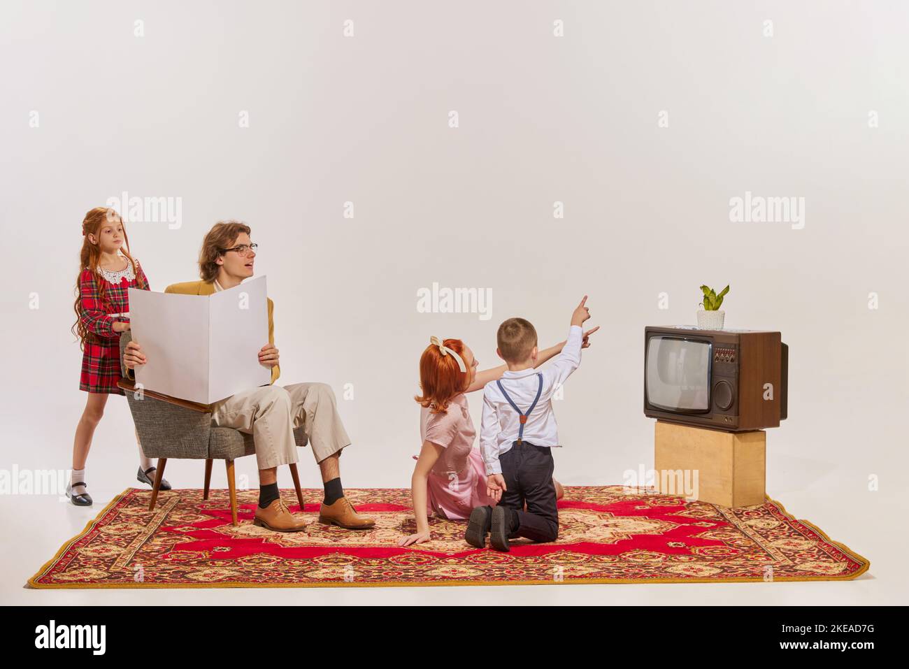 Portrait of young family watching TV isolated over grey background ...