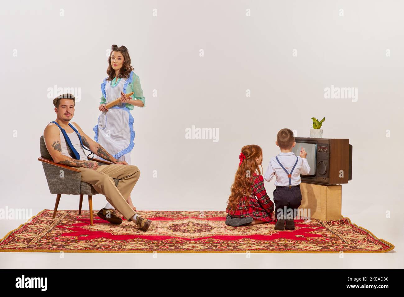 Portrait of young family watching TV isolated over grey background ...