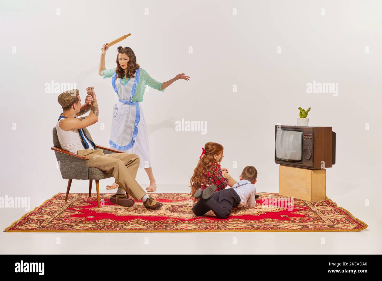 Portrait of young family watching TV isolated over grey background ...