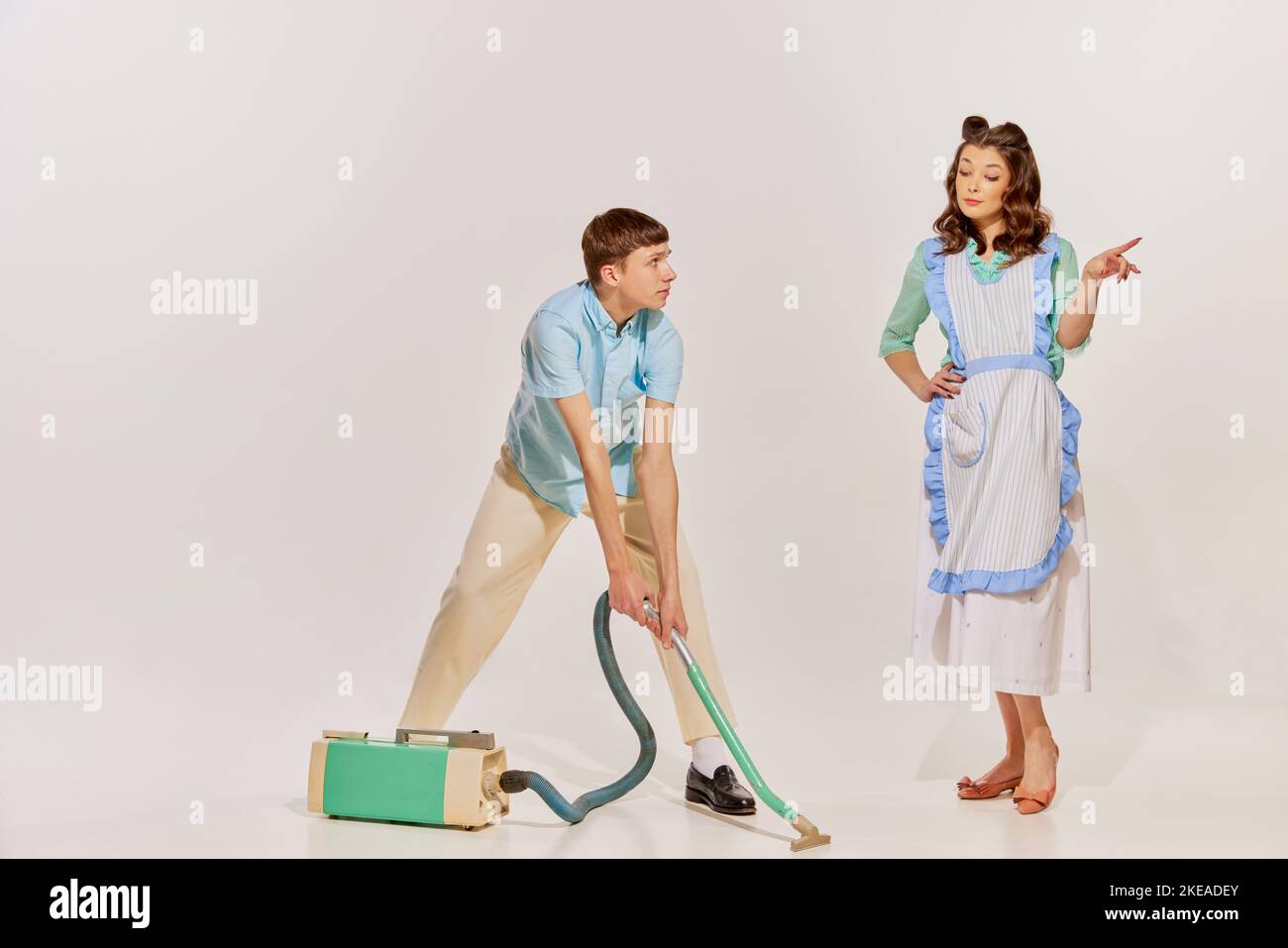 Young beautiful woman, housewife with teen boy cleaning house over grey ...