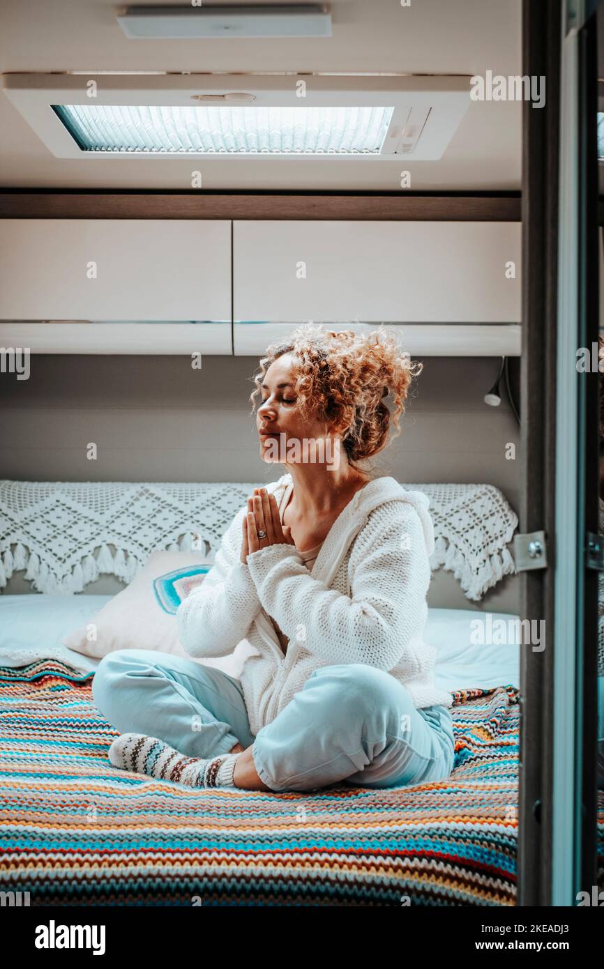 One woman in lotus yoga position meditate inside a camper van in the ...