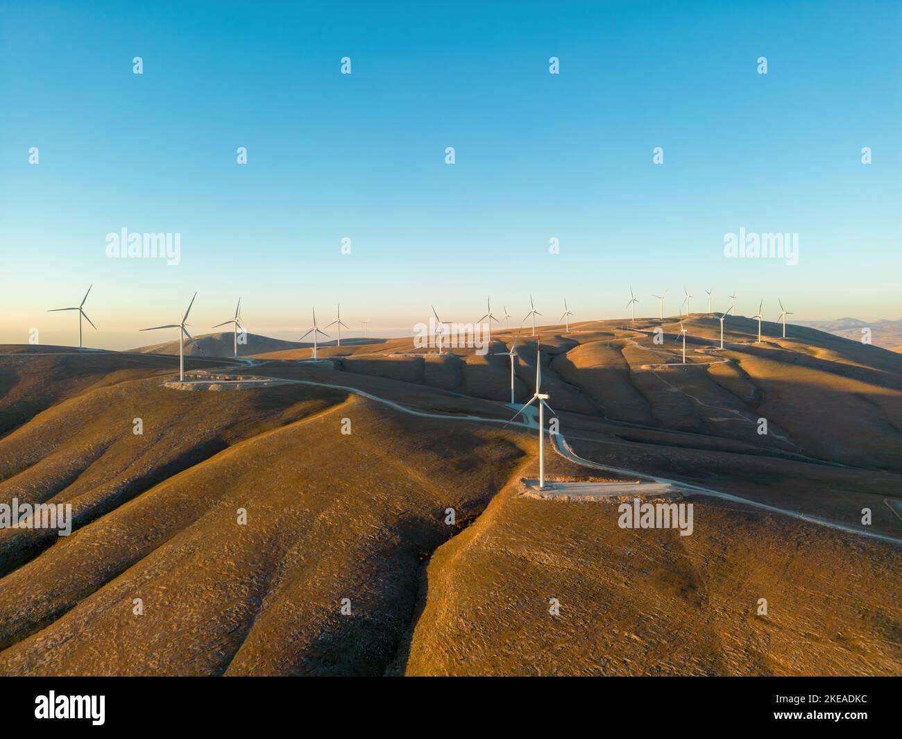 Aerial view of multiple wind turbines standing on a hill and generating ...