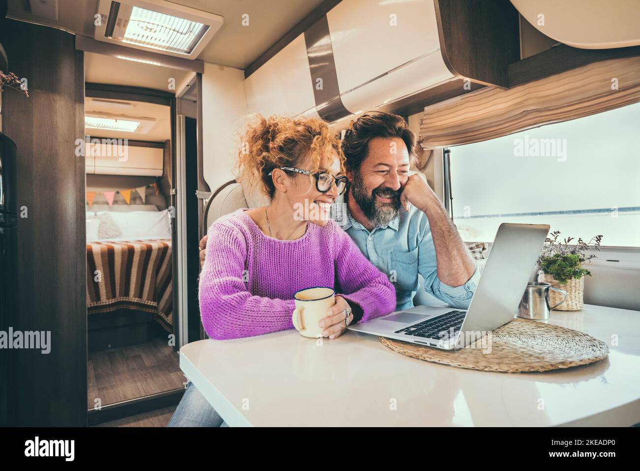 Man and woman using laptop inside camper van during travel lifestyle ...