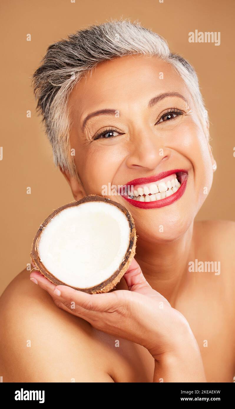 Senior woman, skincare and coconut in studio for beauty, health and ...