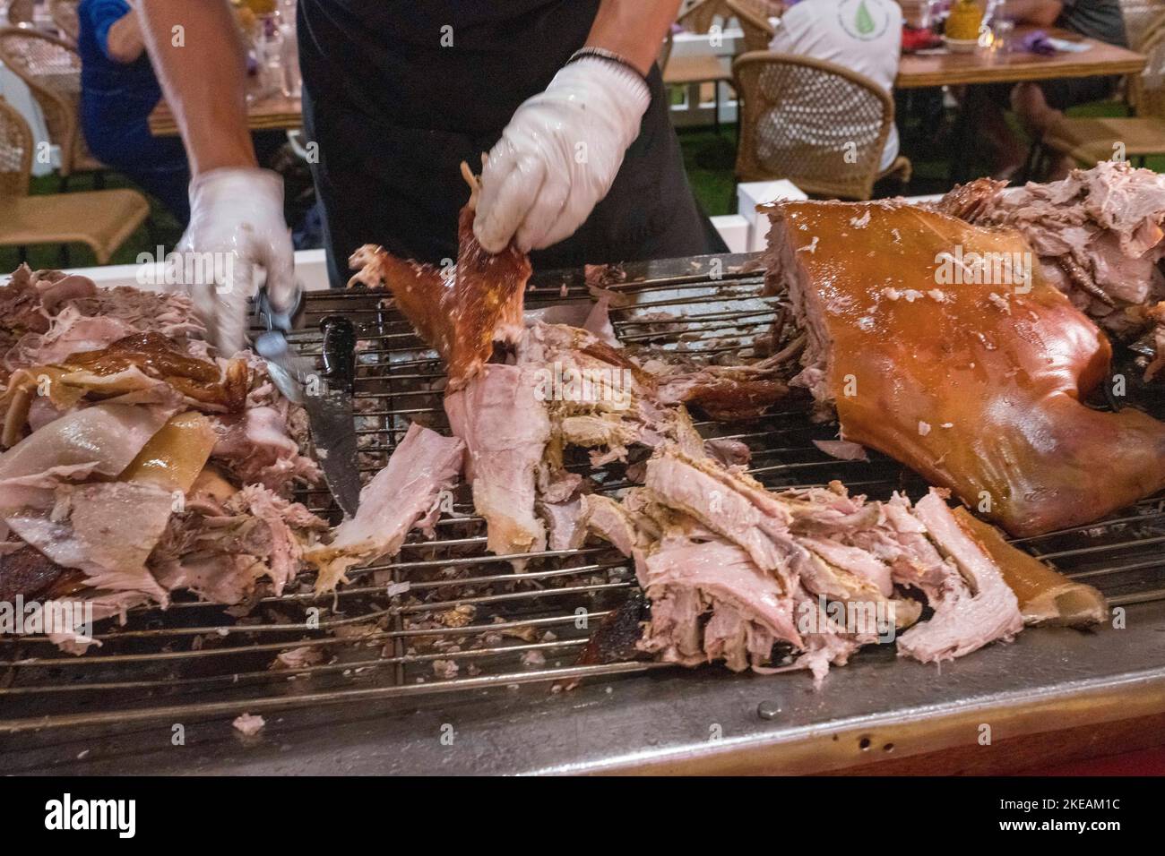 Chef cuts up baked pig pork to serve to guests at buffet Stock Photo ...