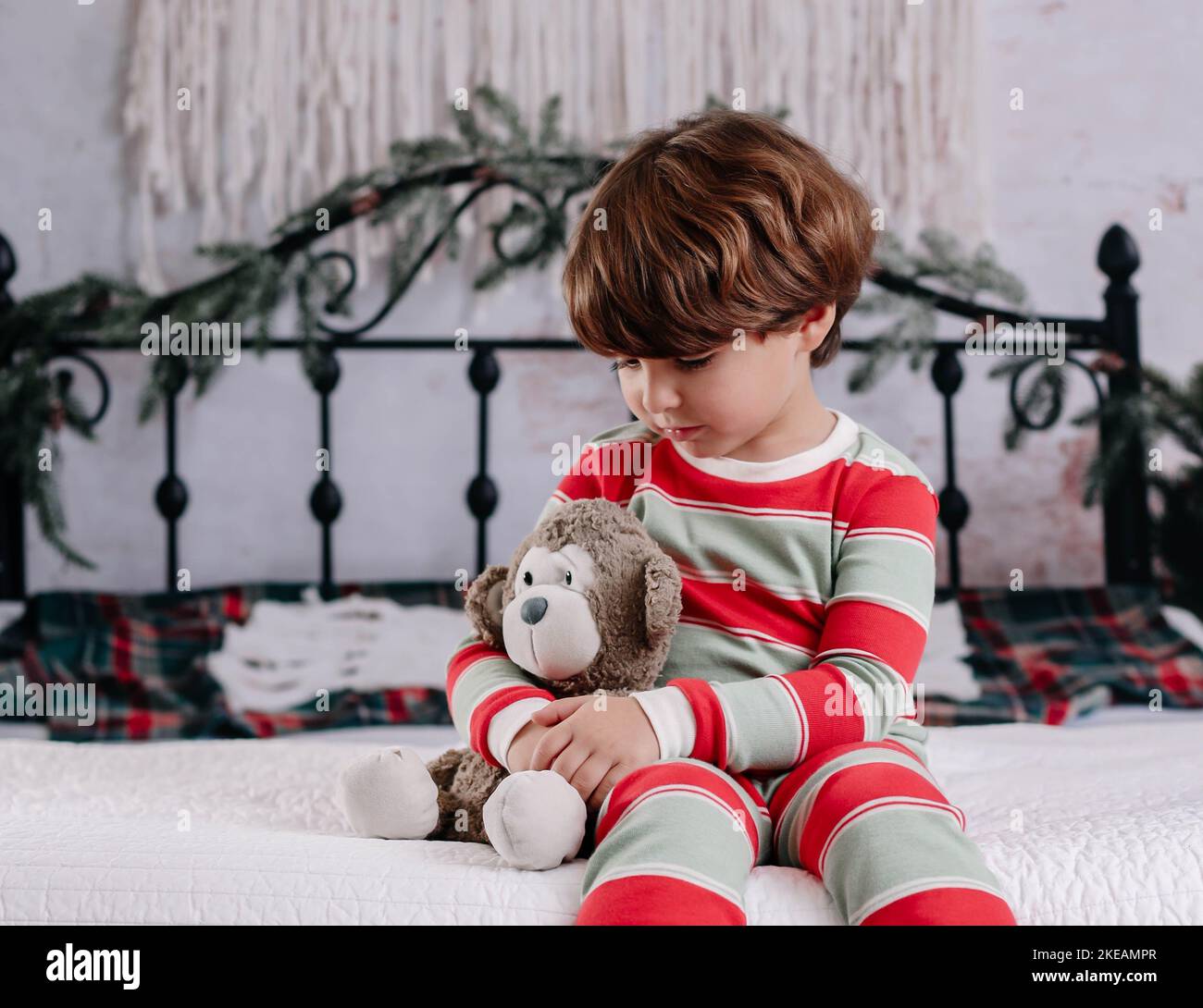 Little cute boy in striped pajamas playing with fluffy monkey toy in ...