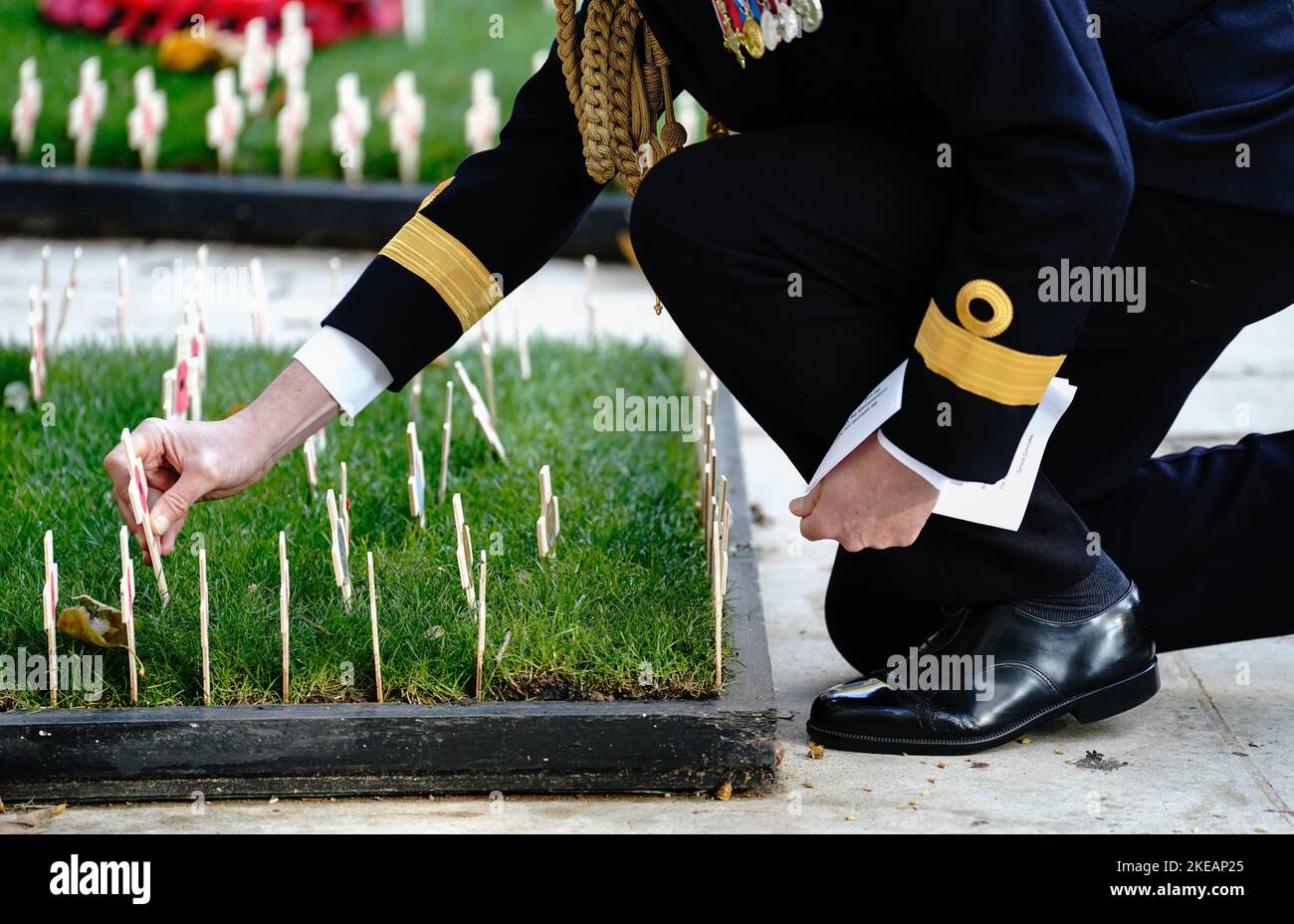 A Royal Navy Commodore plants a cross of remembrance during an ...