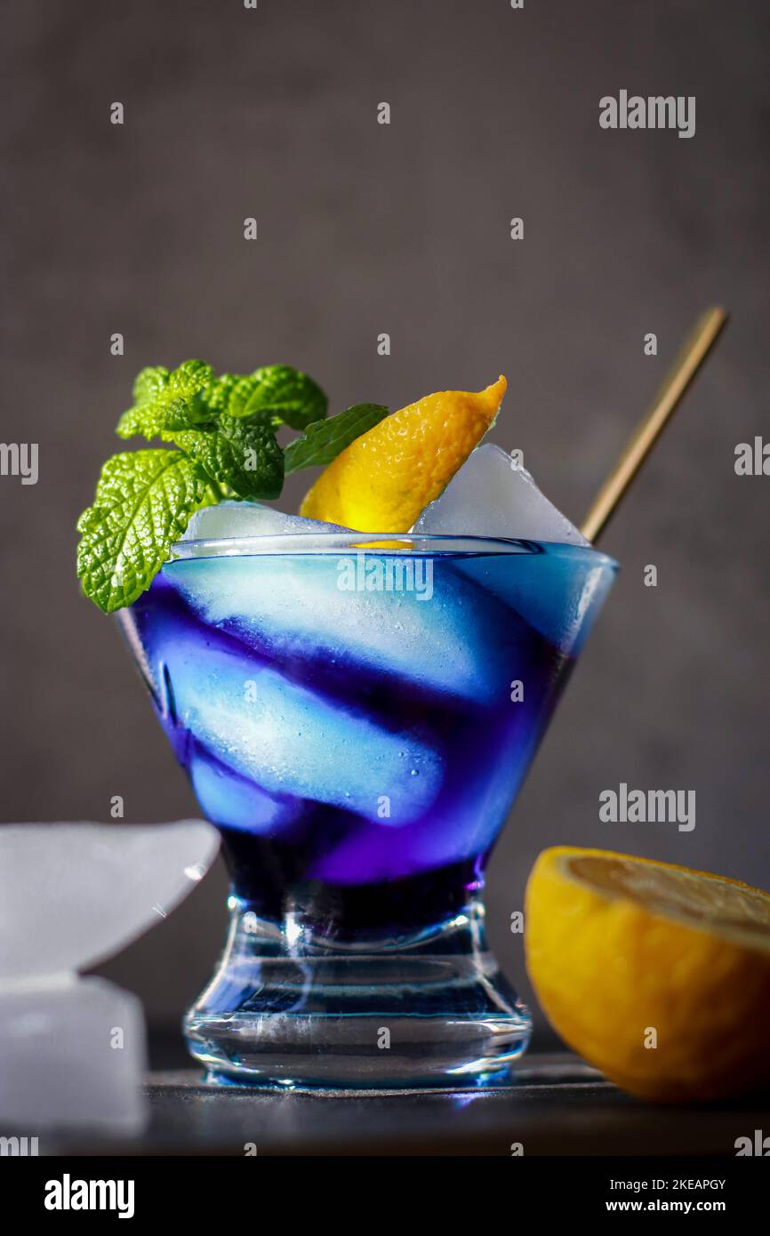 Close up of blue lagoon cocktail with ice, mint and lemon, grey ...