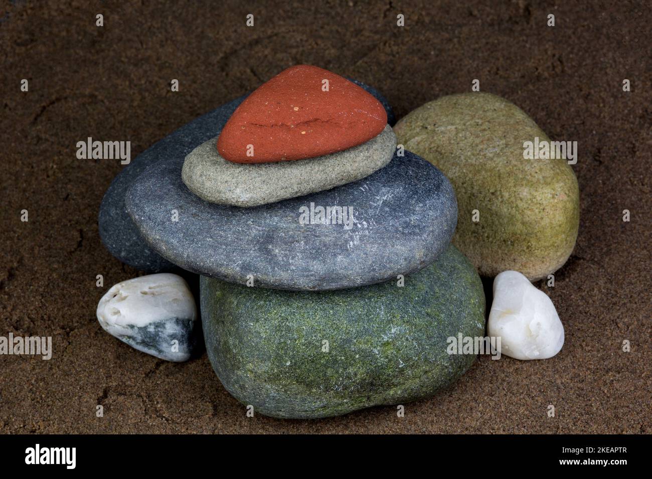 Assorted rocks and pebbles piled on a wet sandy beach Stock Photo - Alamy