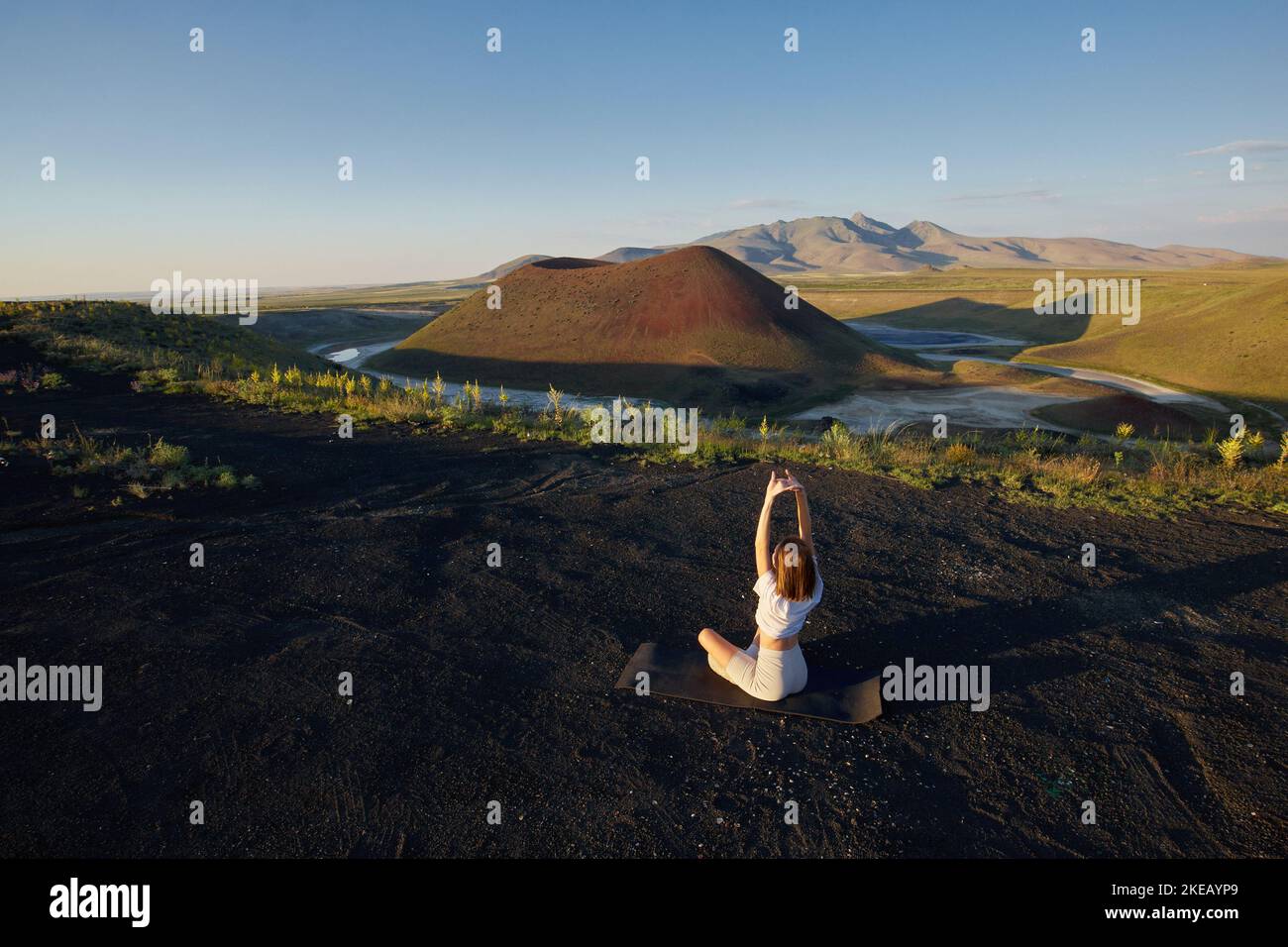 A young woman is standing in a yoga pose against the beautiful nature ...