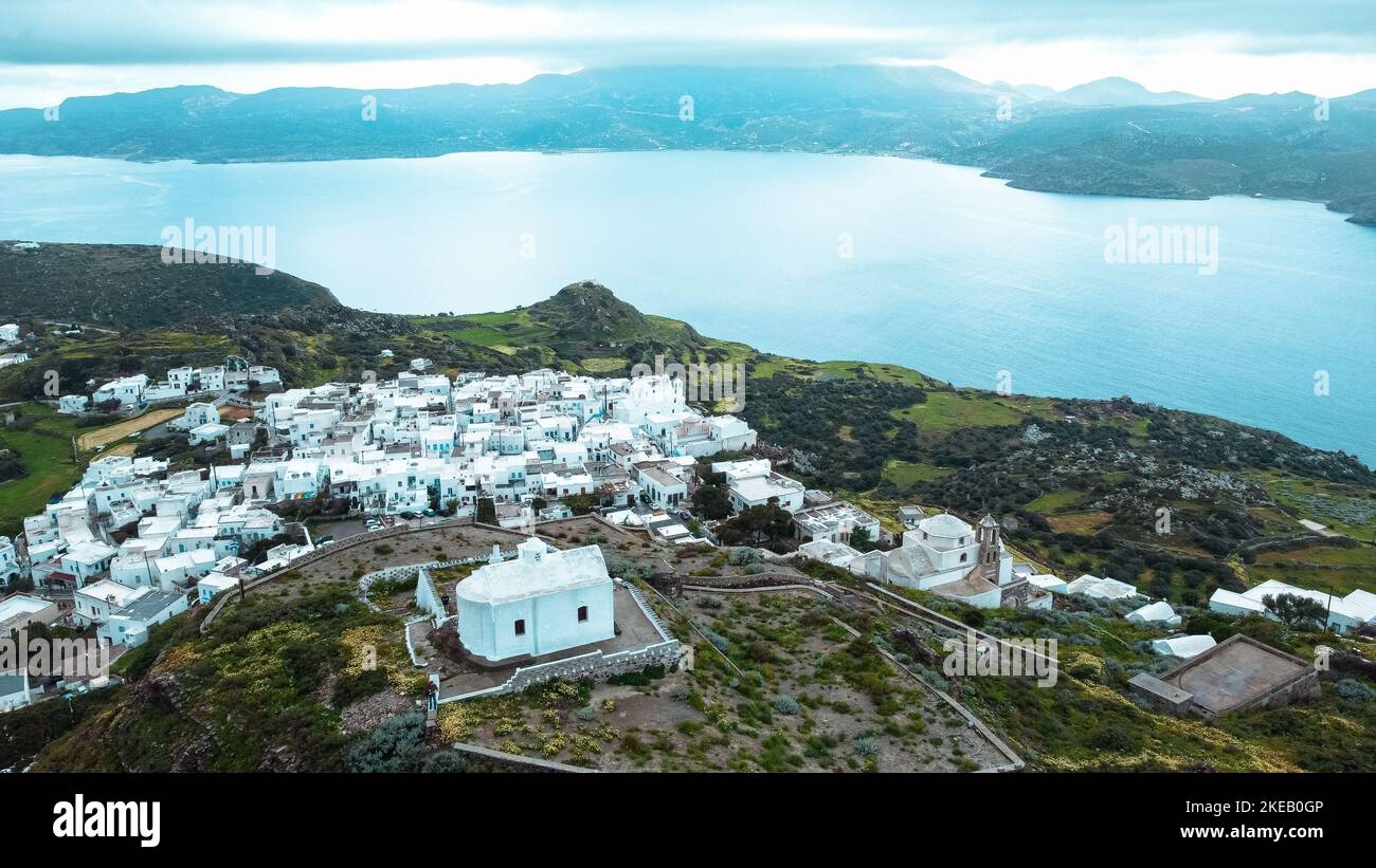 An aerial of white buildings of Milos overlooking the sea in Greece ...