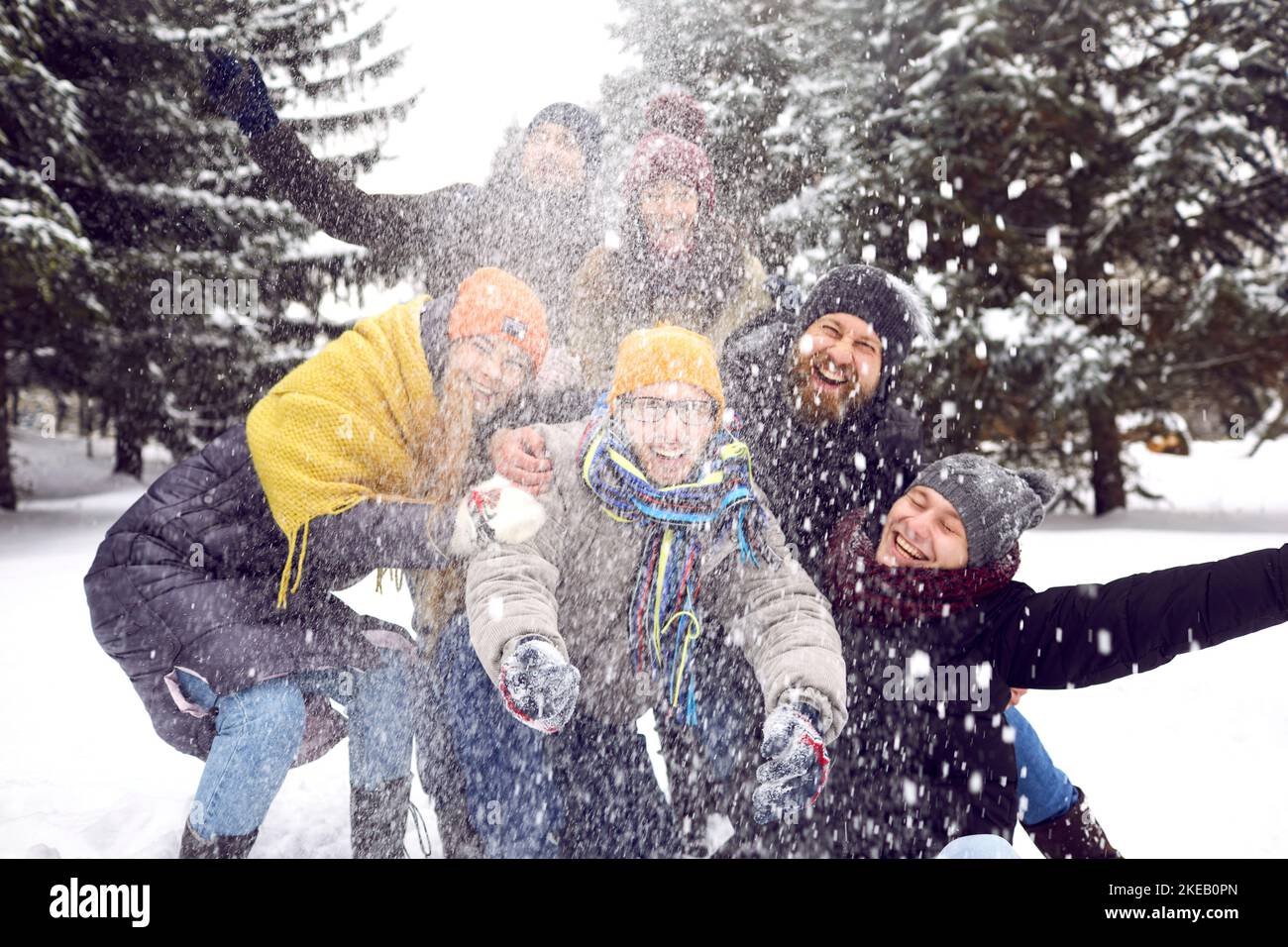 Group of happy young friends having fun and throwing snow in the air in ...