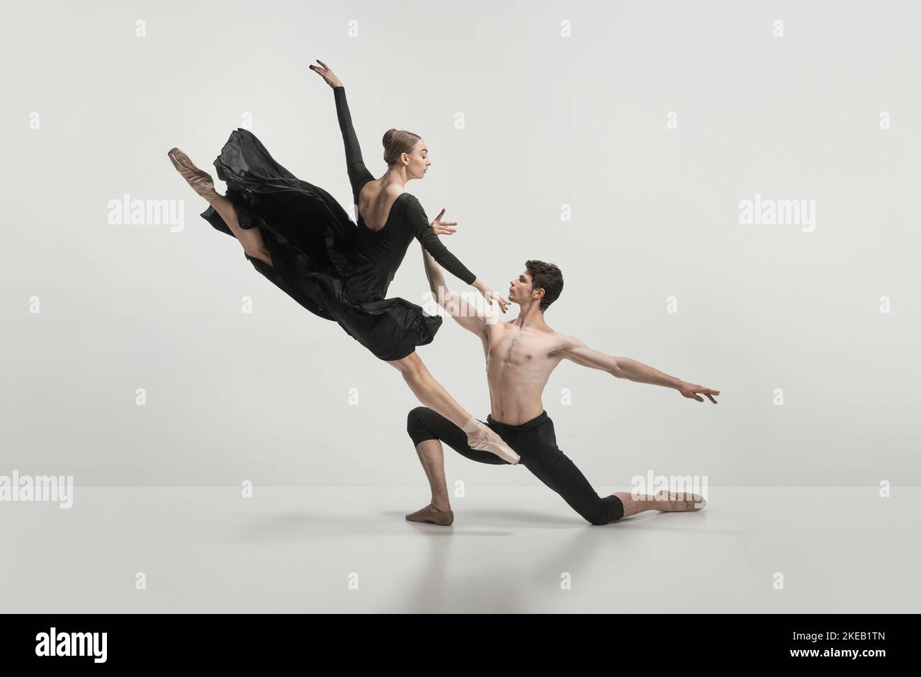 Young man and woman, ballet dancers performing isolated over grey ...