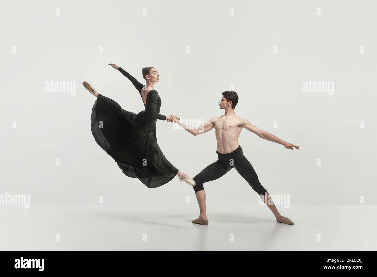 Young man and woman, ballet dancers performing isolated over grey ...
