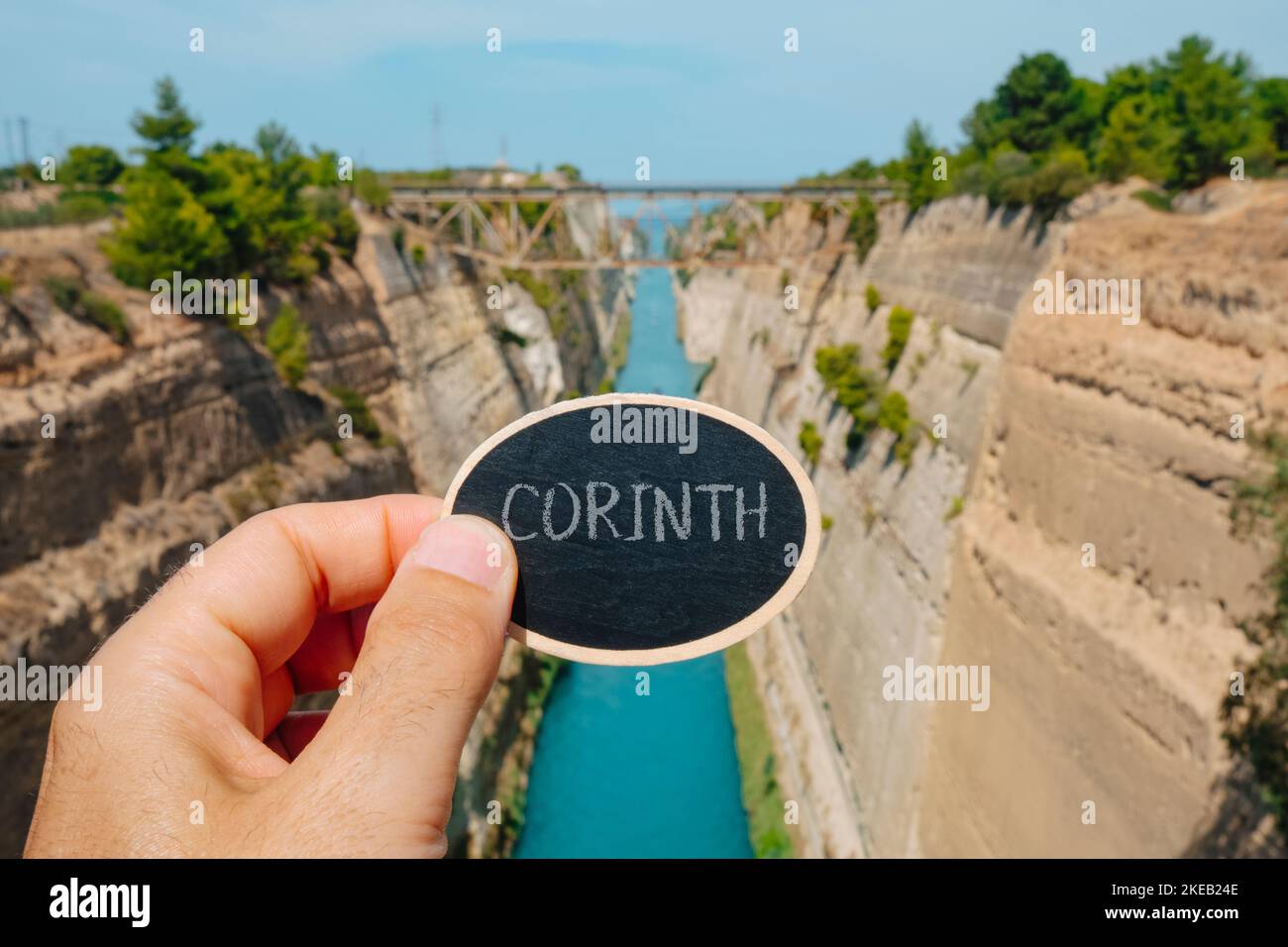 closeup of a man holding a black sign with the text Corinth written in ...