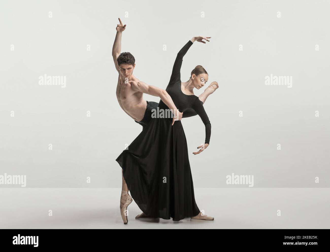 Young man and woman, ballet dancers performing isolated over grey ...