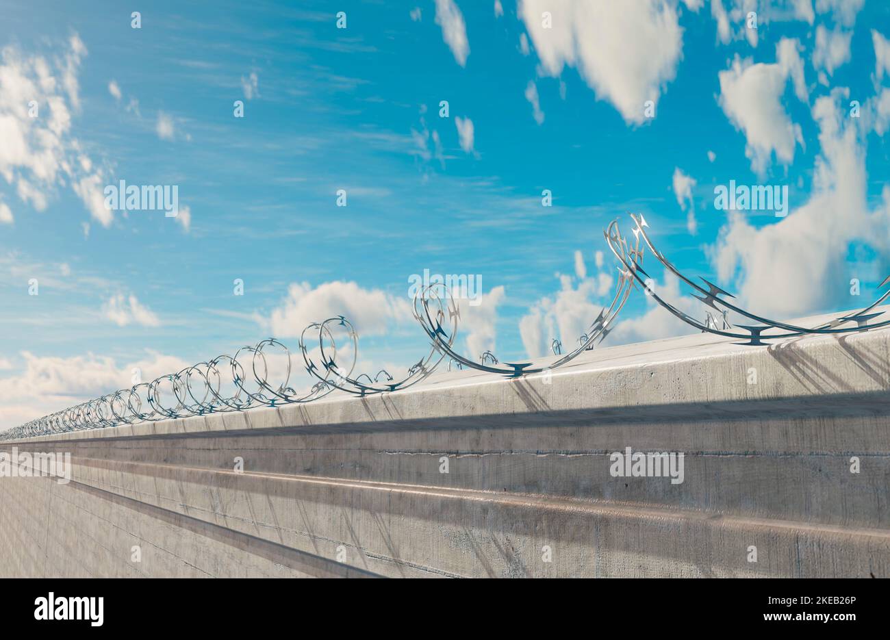 A massively high concrete security boundary wall topped with barbed ...