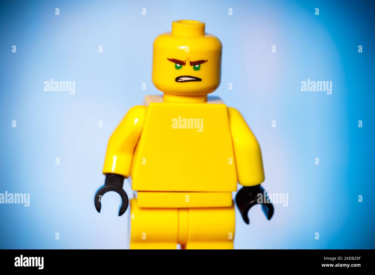 yellow lego figure with a sarcastic face on a blue background. High ...