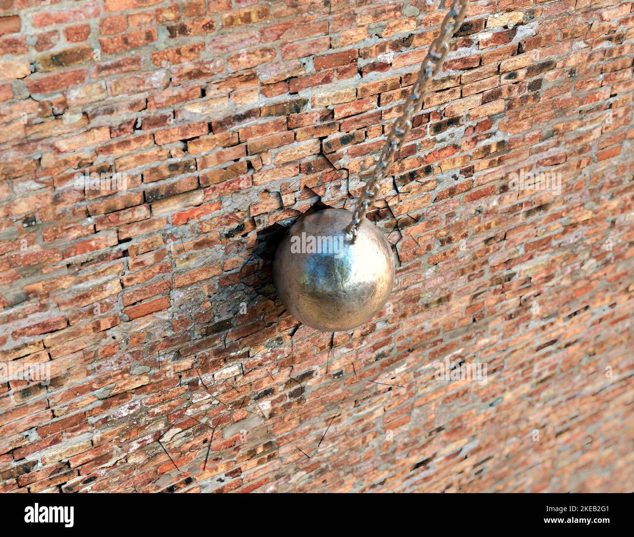 A regular metal wrecking ball attached to a chain breaking a hole in a ...