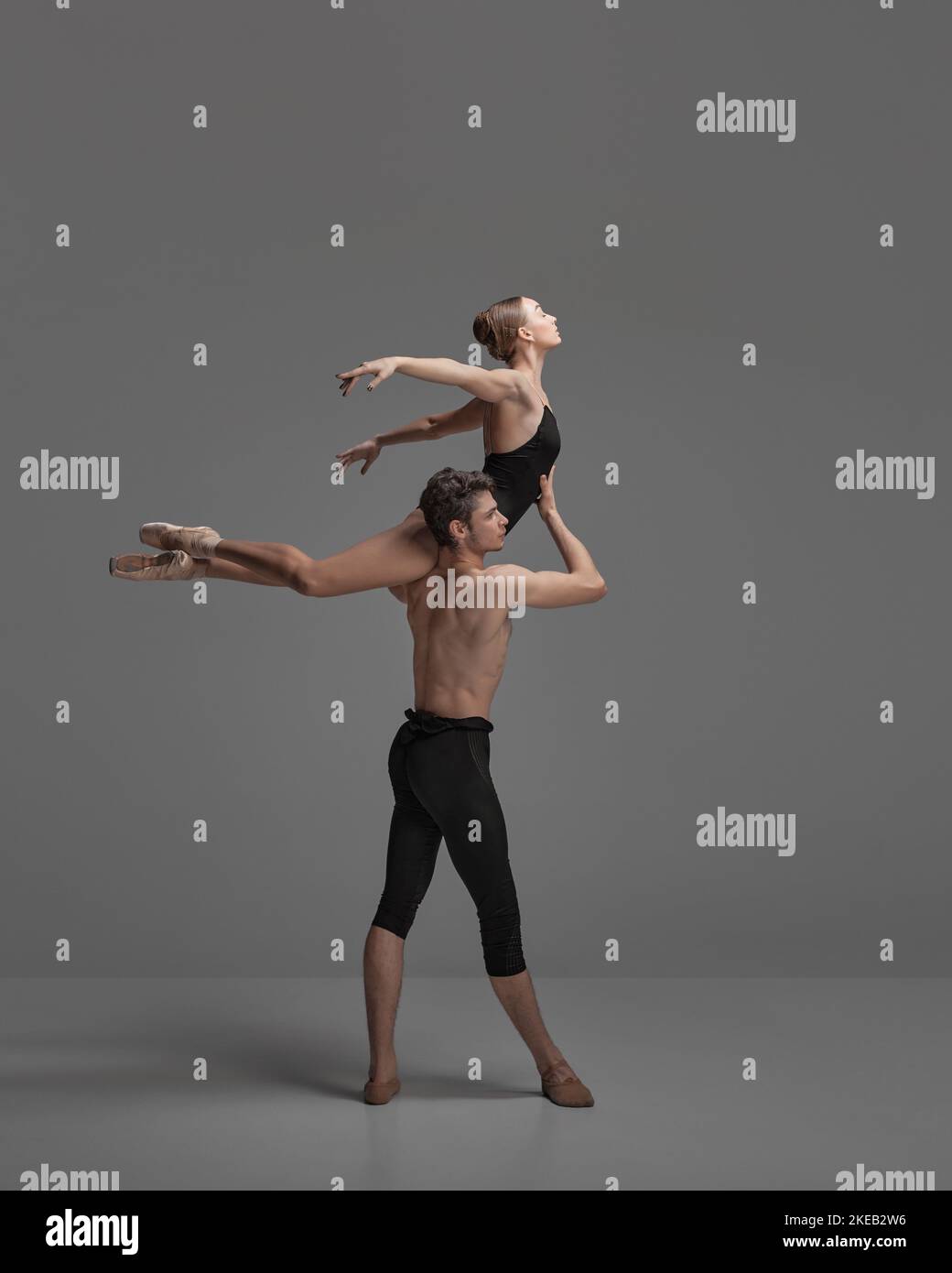 Young man and woman, ballet dancers performing isolated over dark grey ...