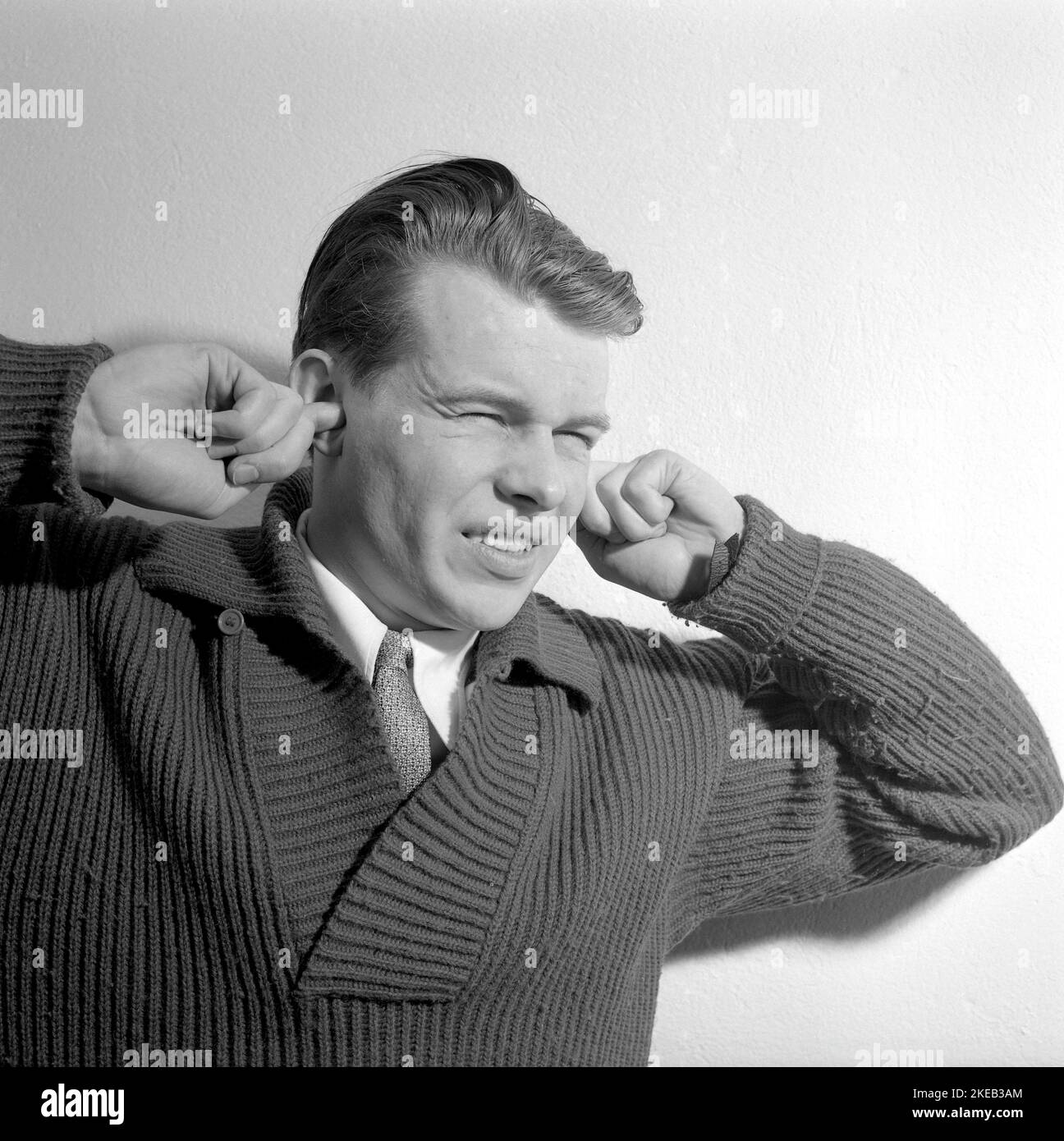 In the 1950s. A young man holds his hands over his ears and has a ...