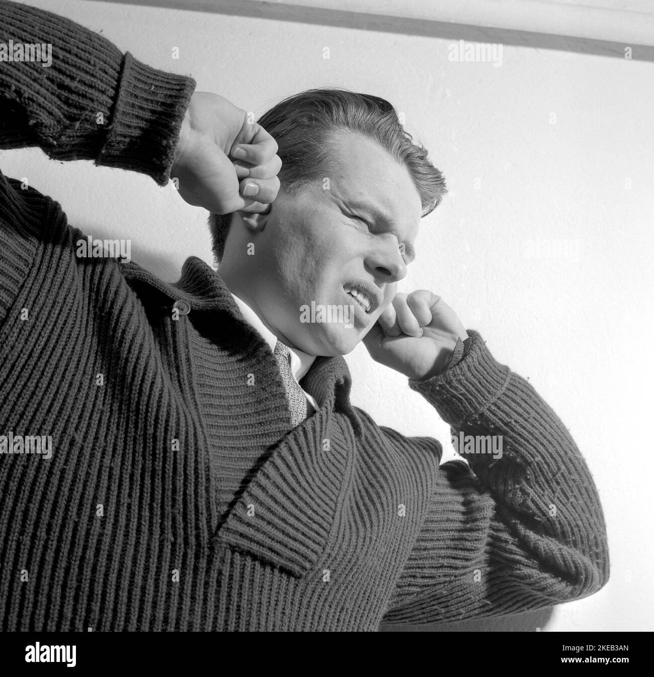 In the 1950s. A young man holds his hands over his ears and has a ...