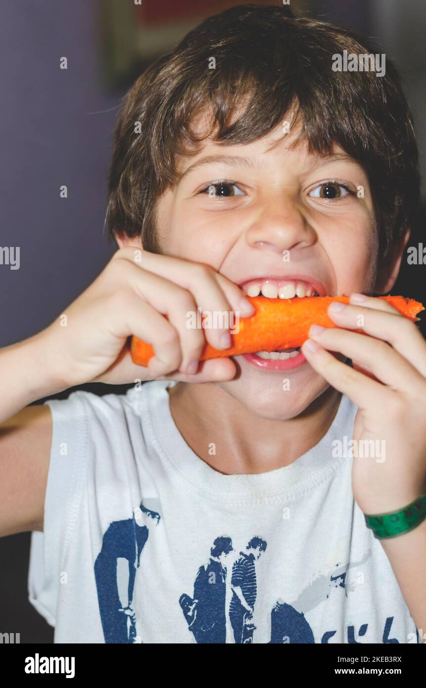 Happy little boy eating a fresh carrot and having fun. Healthy ...