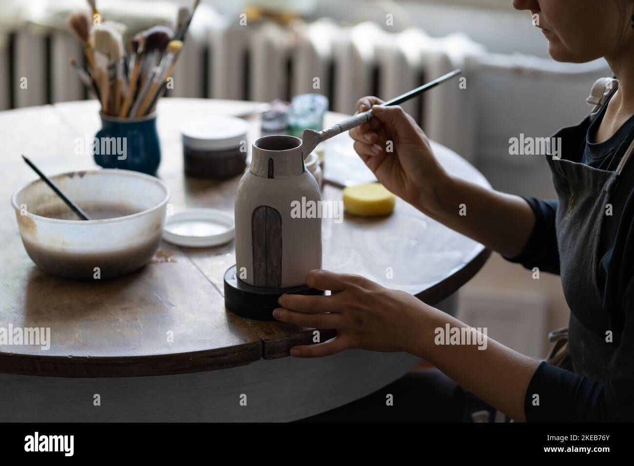 Professional woman owner small pottery business holds brush in hands ...
