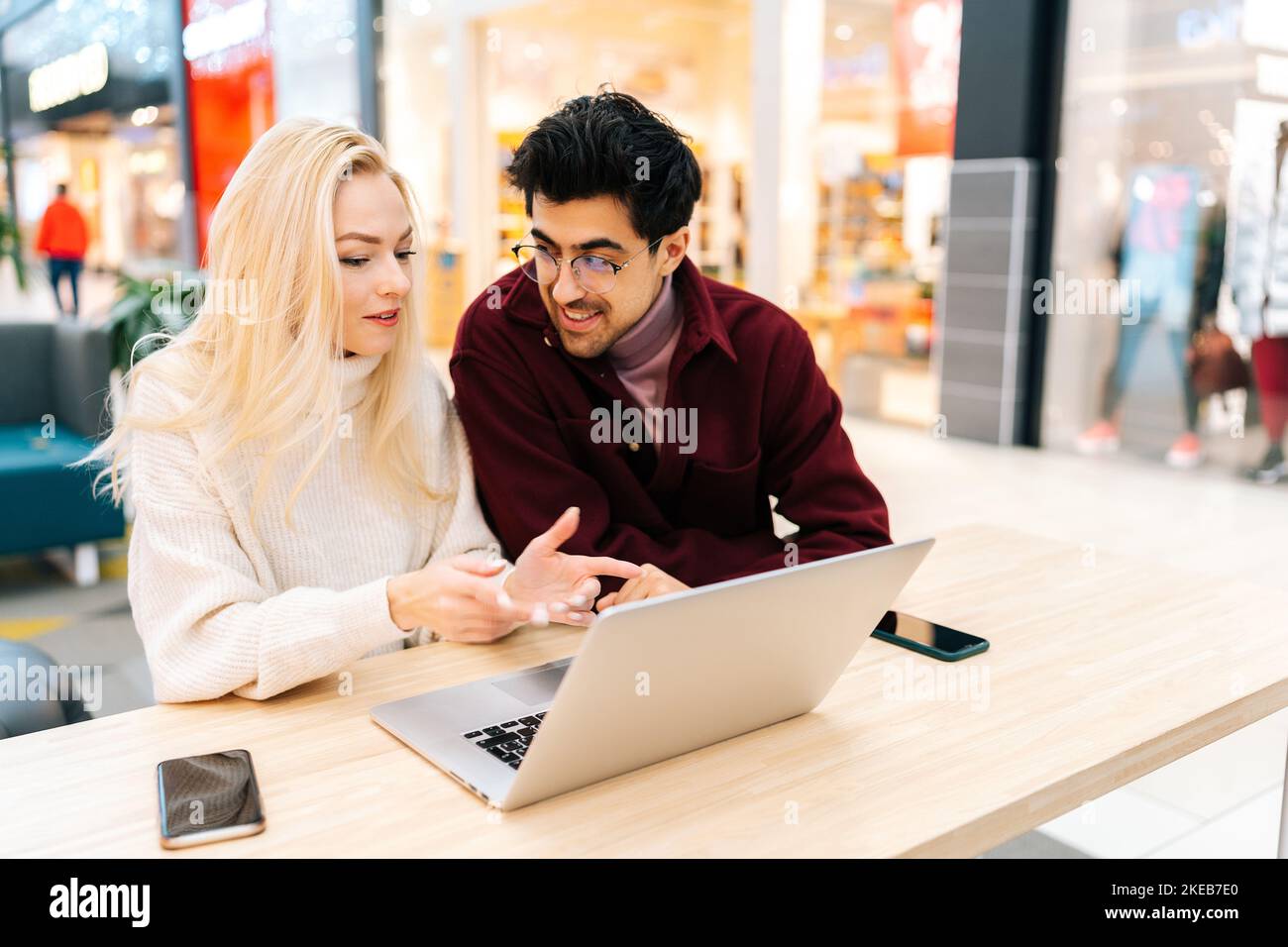 Happy young couple using typing laptop computer together, discussing ...