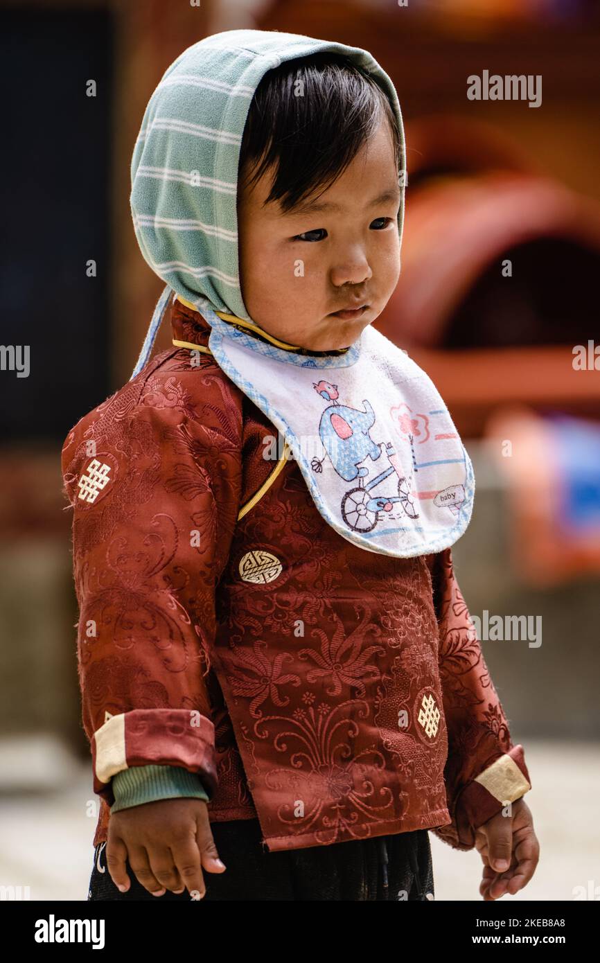 A closeup shot of a child in traditional clothes, with a bib around its ...
