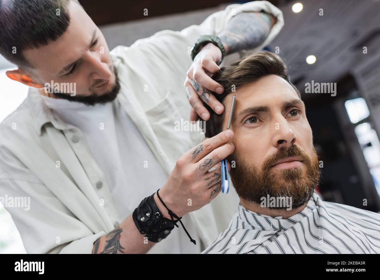 brunette bearded man near barber shaving his forehead with straight ...