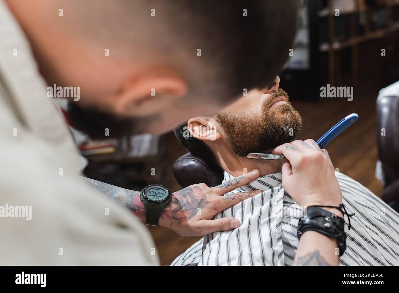 blurred hairdresser shaving neck of client with straight razor in ...