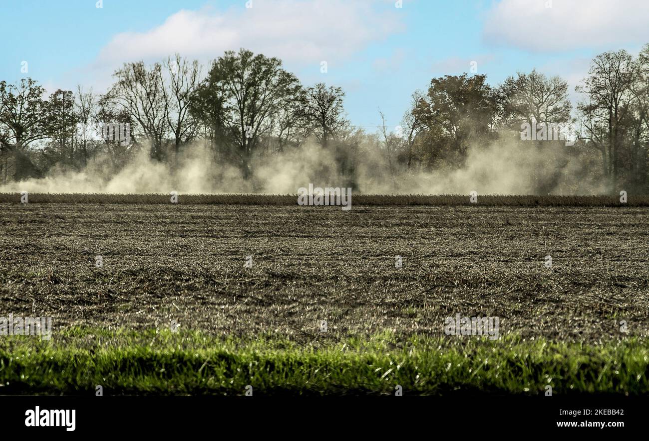Farmer plowing his fields with leaving a trail of dust Stock Photo - Alamy