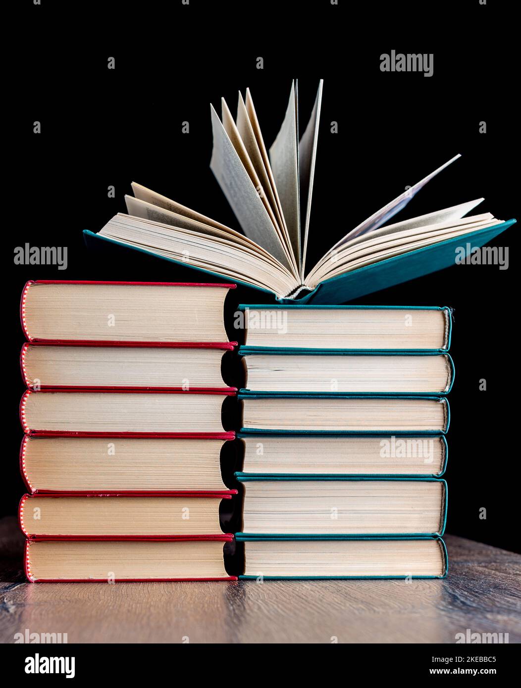 Two stacks of hardcover paper books and one open. Dark background, copy ...