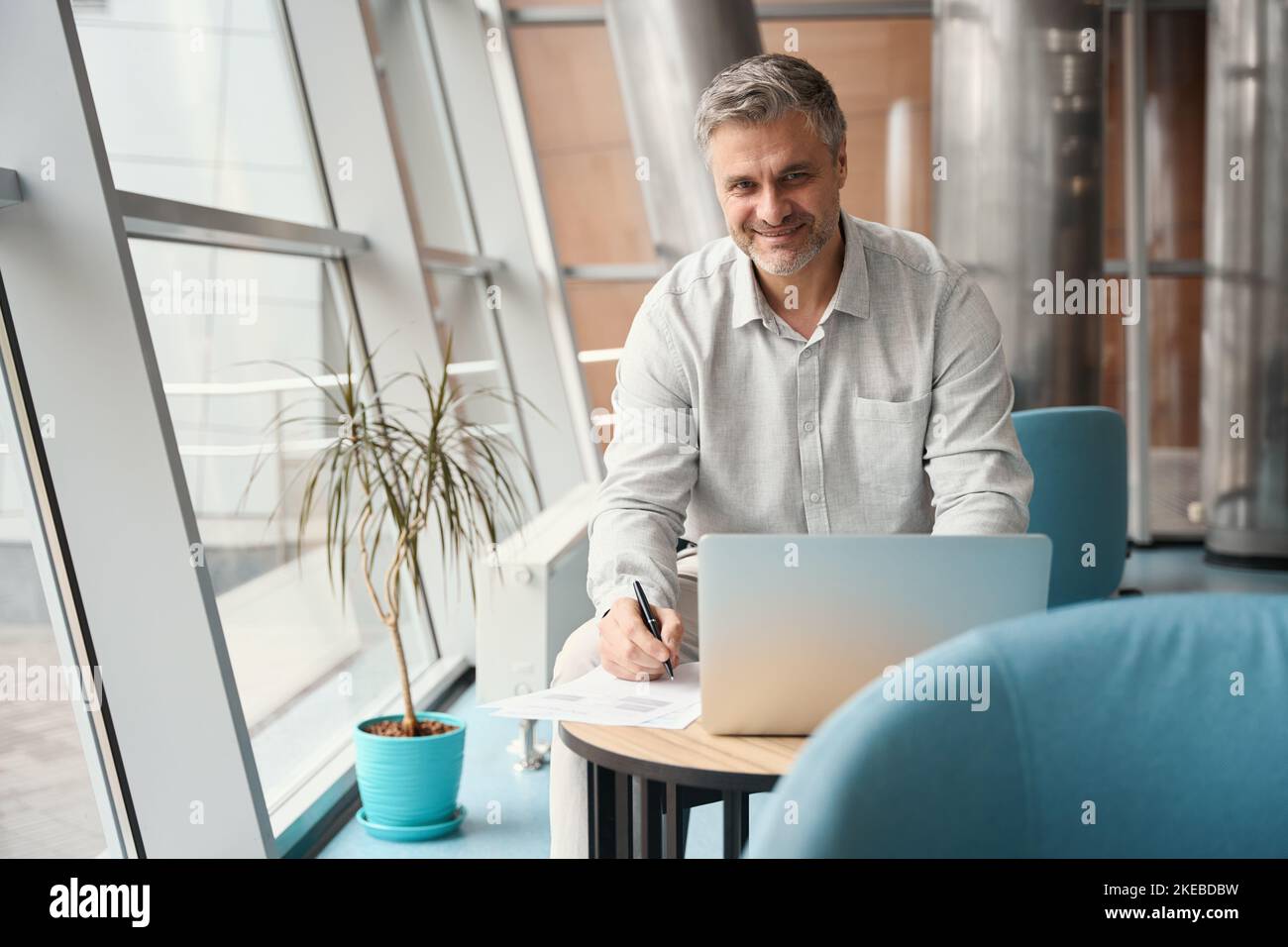 Man signs papers in a coworking space among plants Stock Photo - Alamy