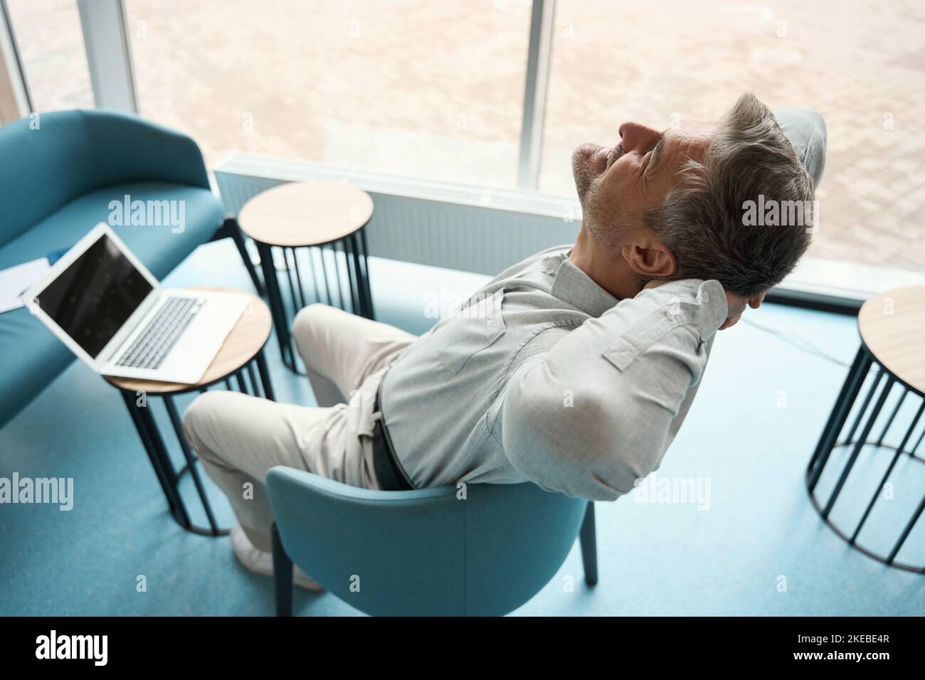 Employee is relaxing in a coworking area with upholstered furniture ...