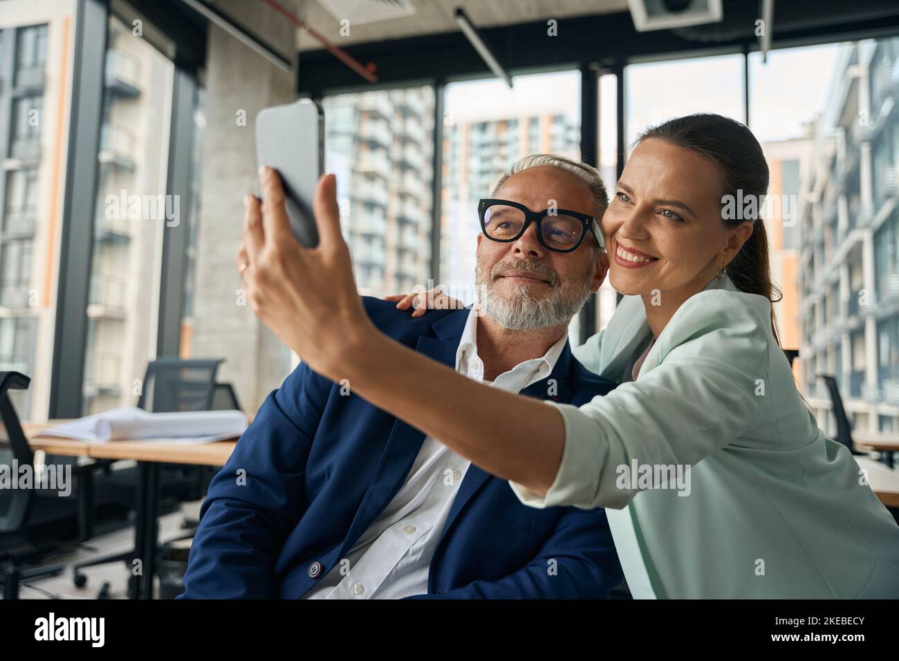 Jolly couple taking selfie during work in office together Stock Photo ...